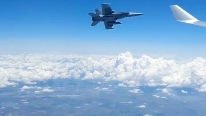 一架F18战斗机在伴飞客机时 除了亮腹展示武器外还做了战术动作并打出照明弹_哔哩哔哩_bilibili